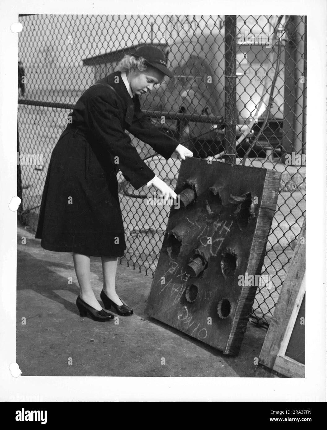 Photograph of Woman in Naval Dress Examining a Damaged Piece of Armor ...