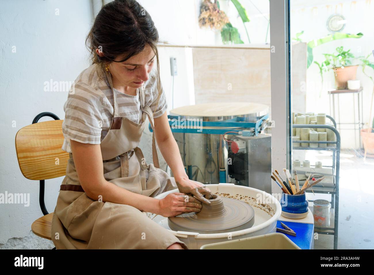 young ceramist on the lathe or potter's wheel working and shaping clay ...