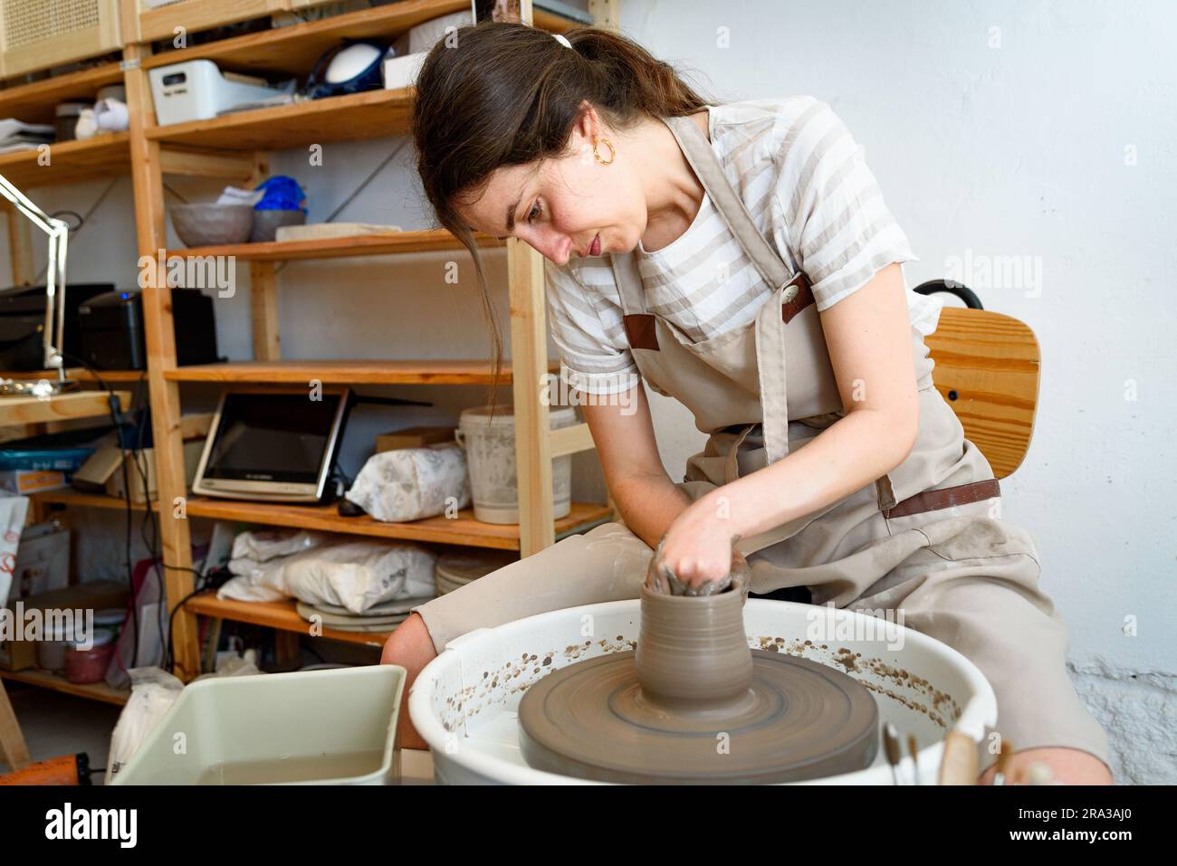 young ceramist on the lathe or potter's wheel working and shaping clay ...