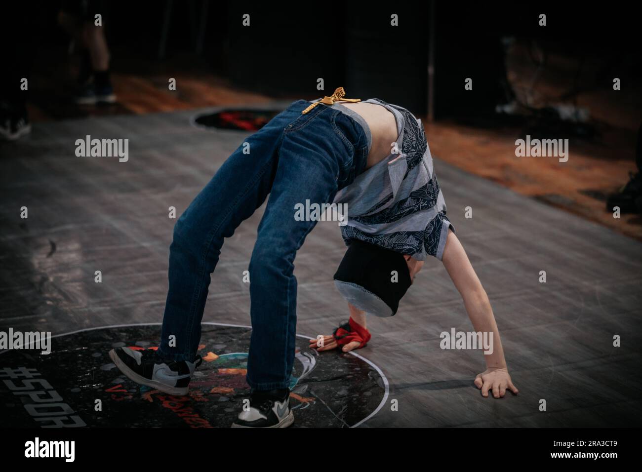 A young adult with long brown hair performing a handstand on a hardwood ...