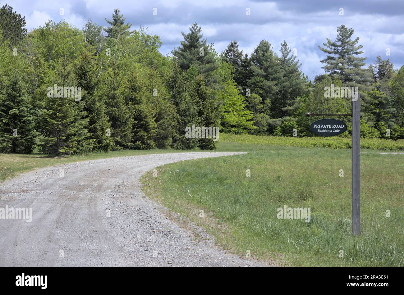 private road (residents only) sign on rural unpaved road with trees, grass, sky and clouds Stock ...