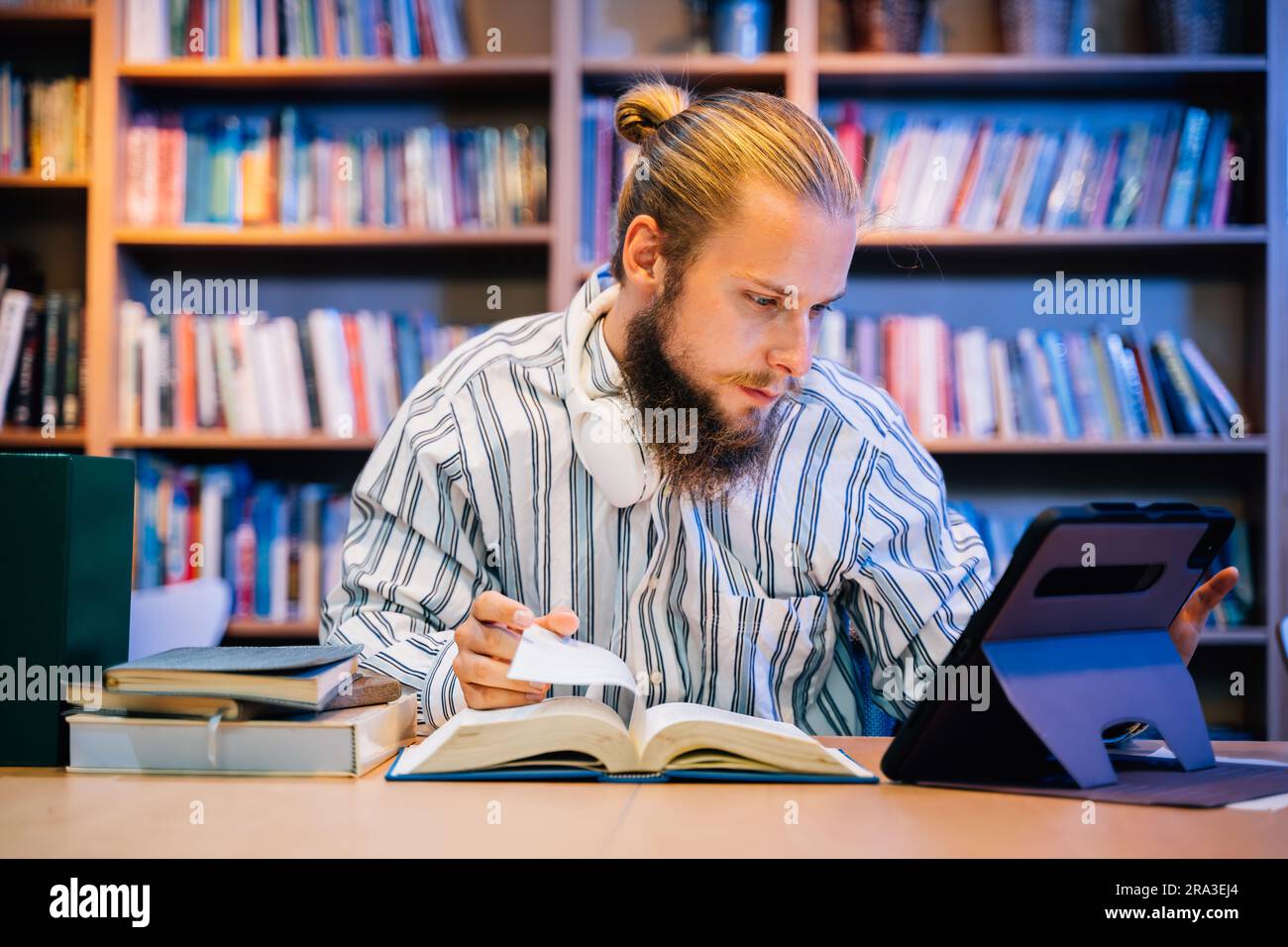 Portrait of man reading books and working in library for education ...