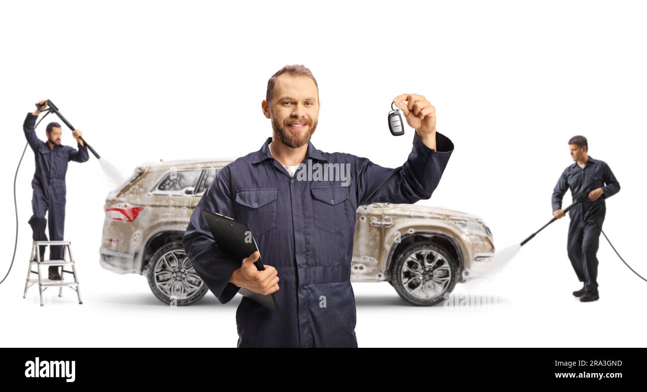 Workers cleaning a vehicle at a car wash and a manager holding a key ...