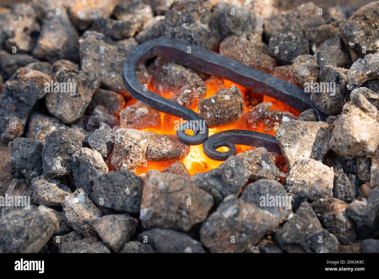 Piece of wrought iron between glowing coals in a forge Stock Photo - Alamy
