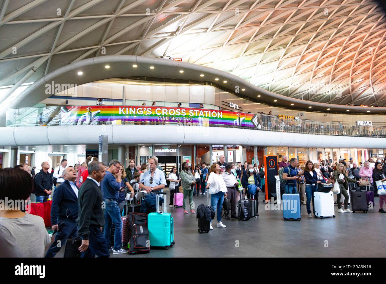 inside kings cross station concourse full of passengers and a pride ...