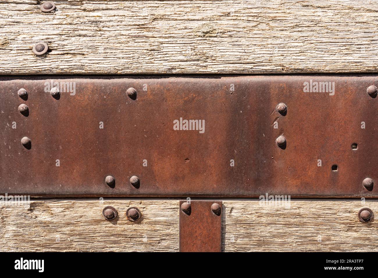 Rusted iron with rivets & bolts holds old weathered wood slabs together ...