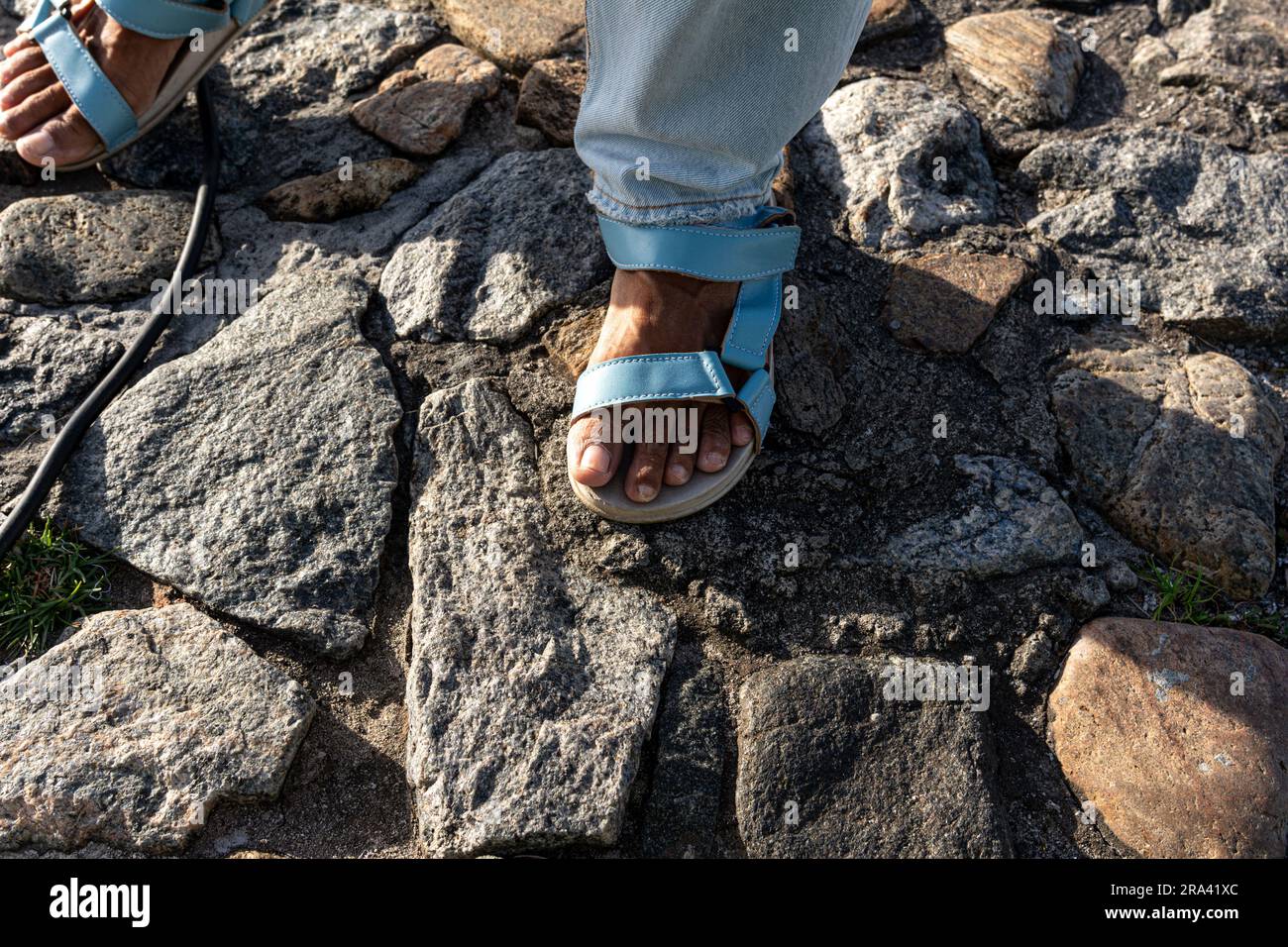 Texture of stones on the ground. A human foot treads the ground ...