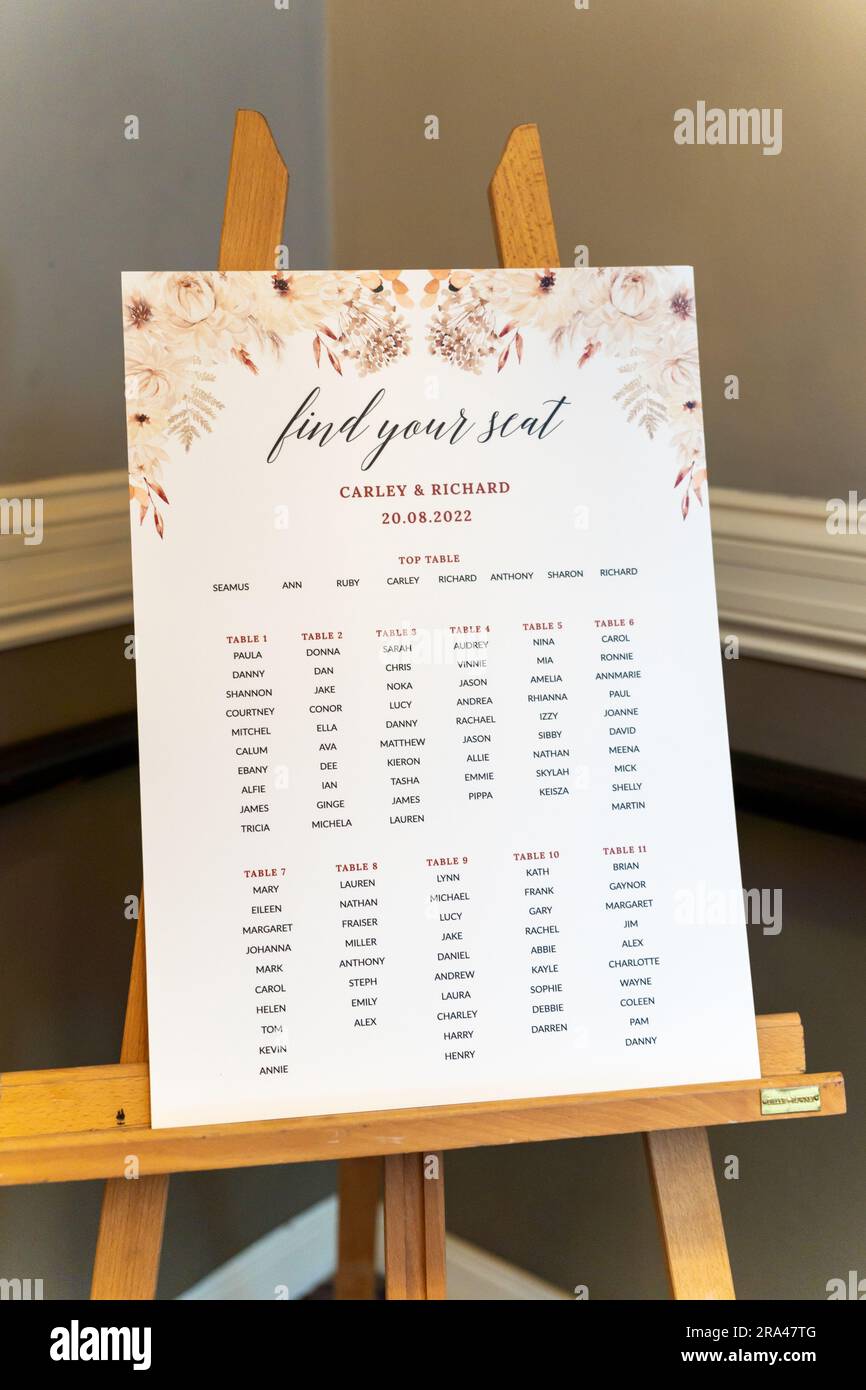 A rustic wooden holder with a written wedding seating card displaying a ...