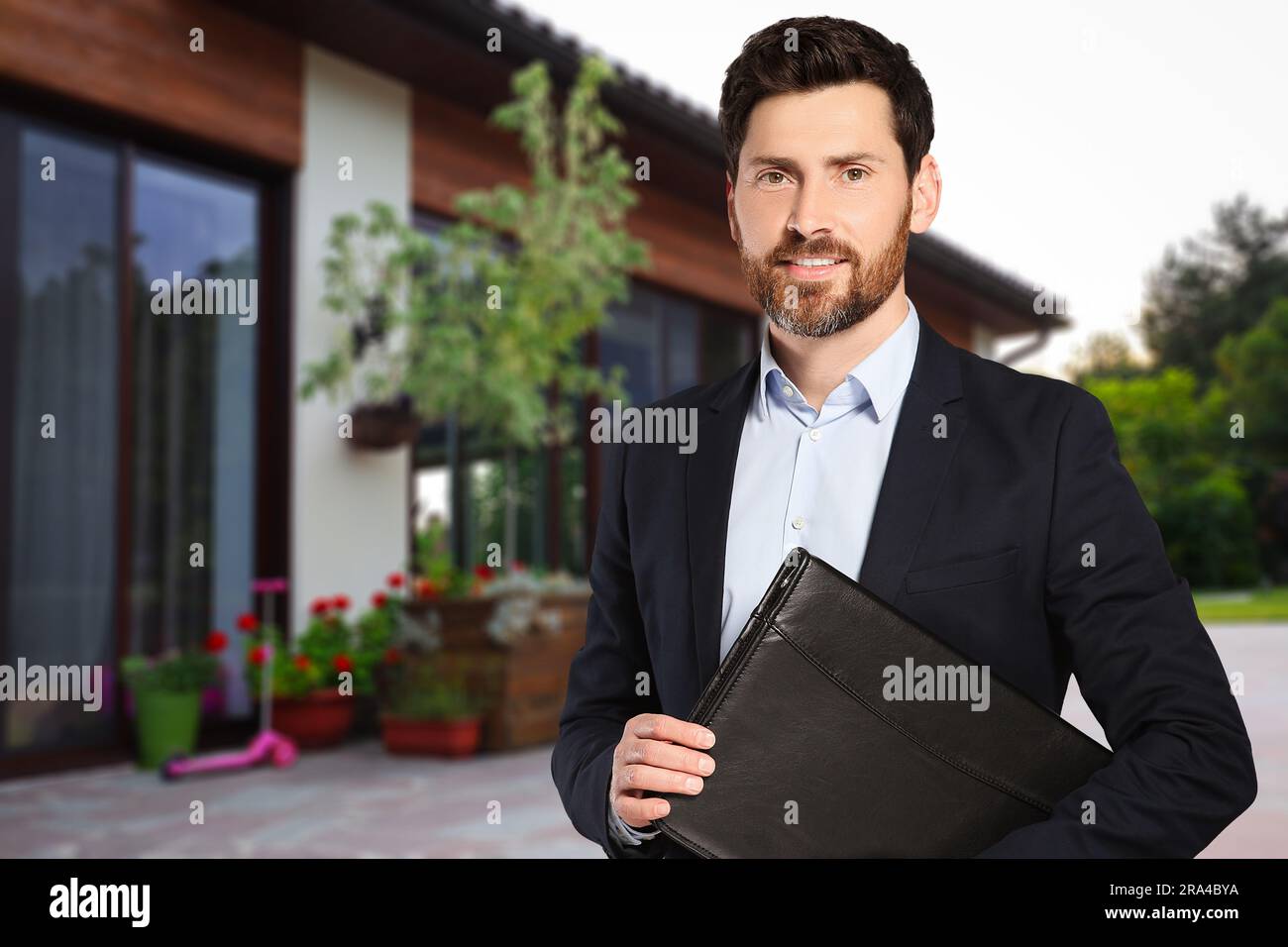 Handsome real estate agent with portfolio near beautiful house outdoors ...