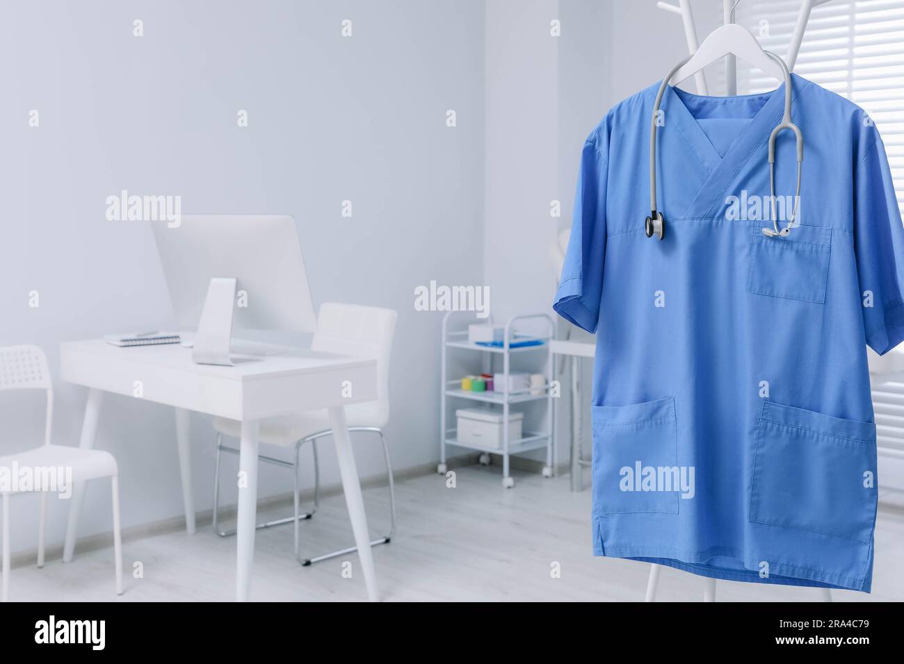 Blue medical uniform and stethoscope hanging on rack in clinic. Space ...