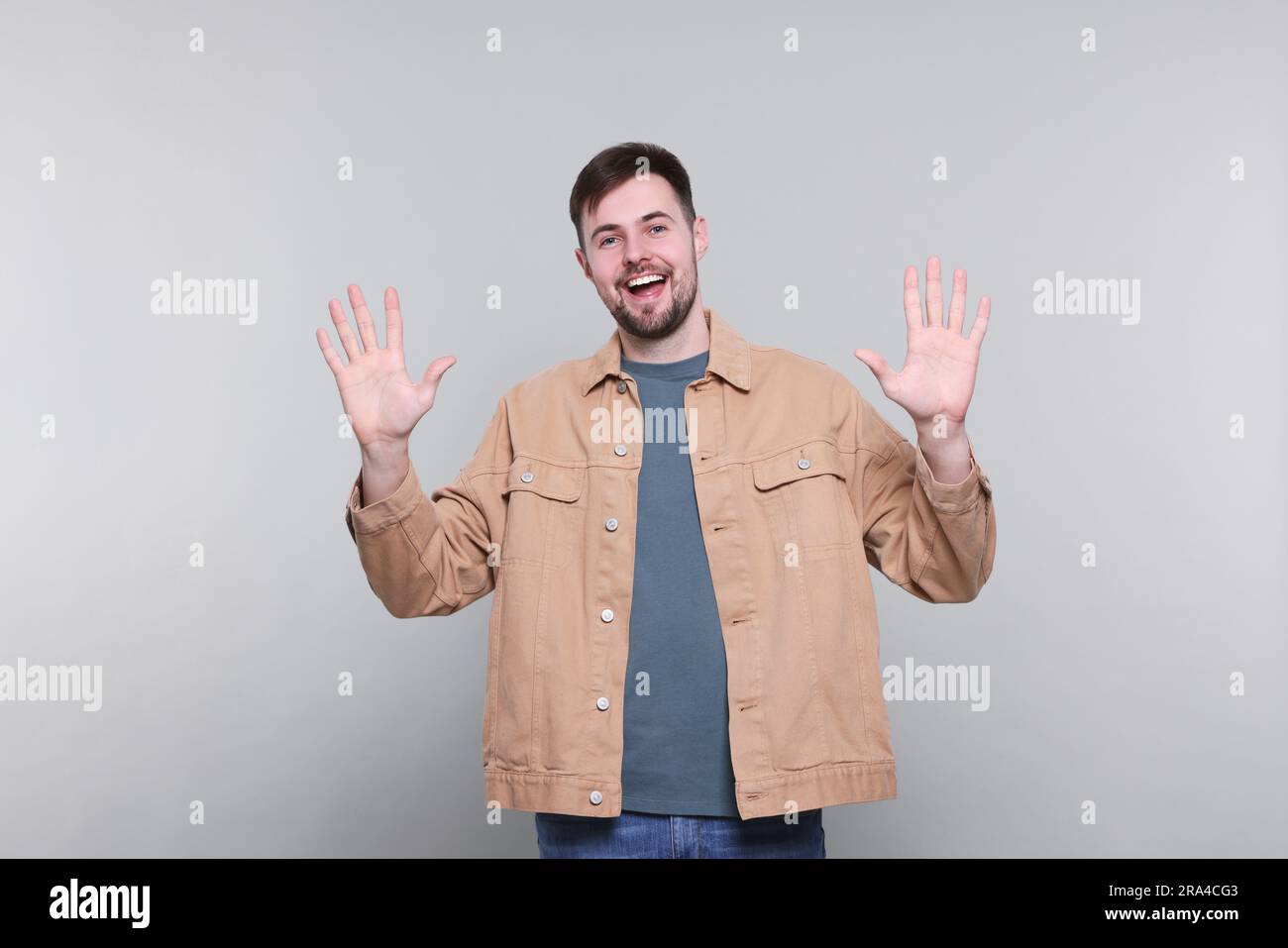 Man giving high five with both hands on grey background Stock Photo - Alamy