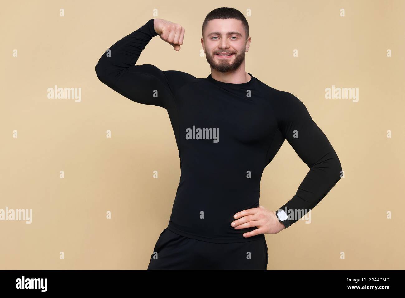 Handsome sportsman showing muscles on brown background, space for text ...