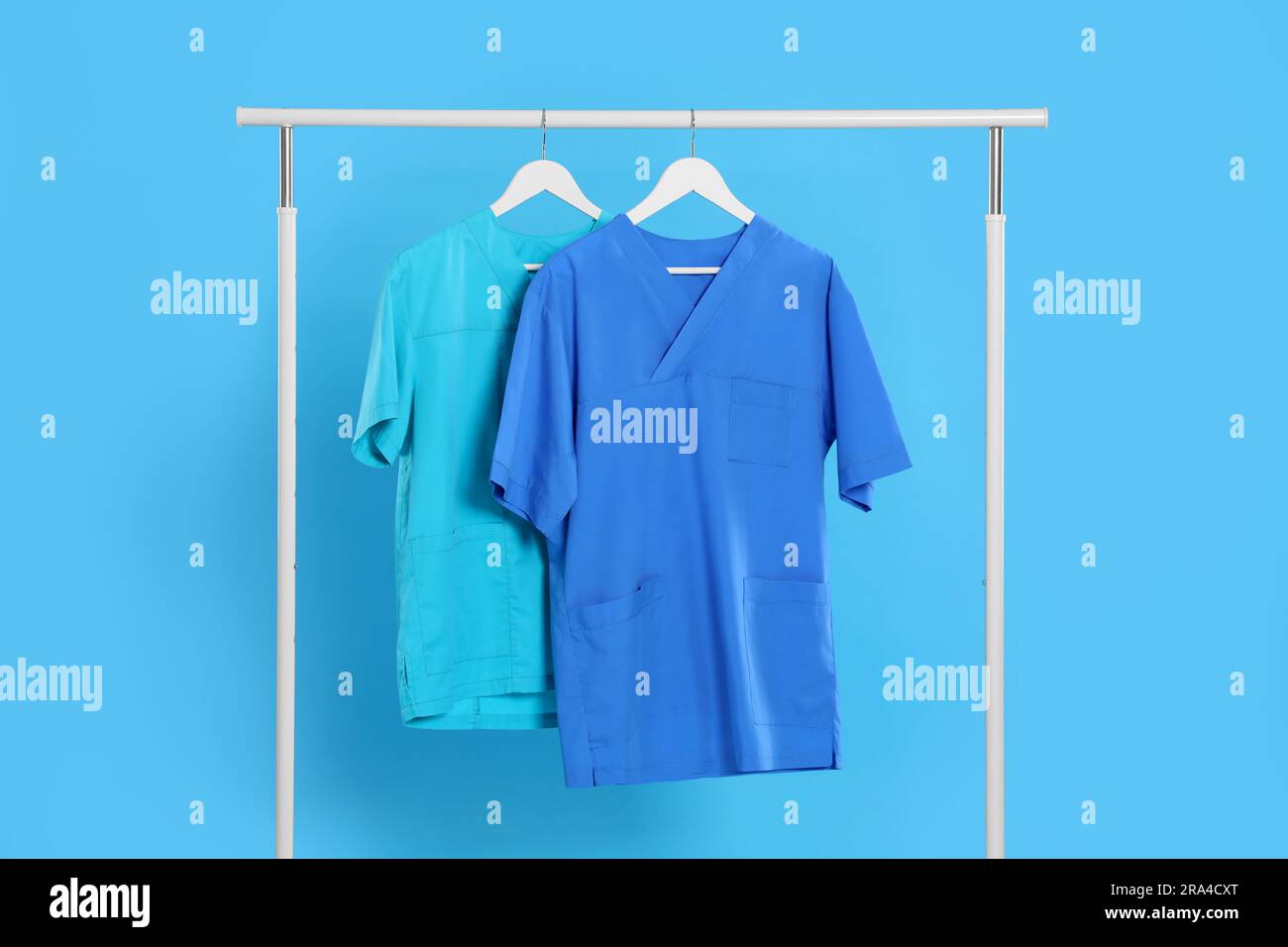 Medical uniforms on rack against light blue background Stock Photo - Alamy