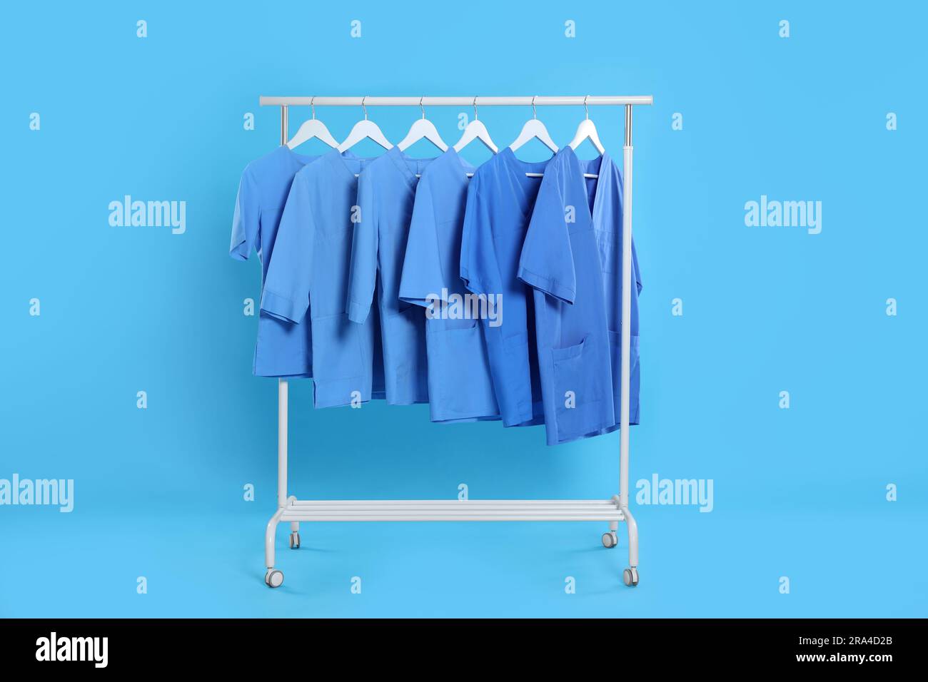 Medical uniforms on rack against light blue background Stock Photo - Alamy