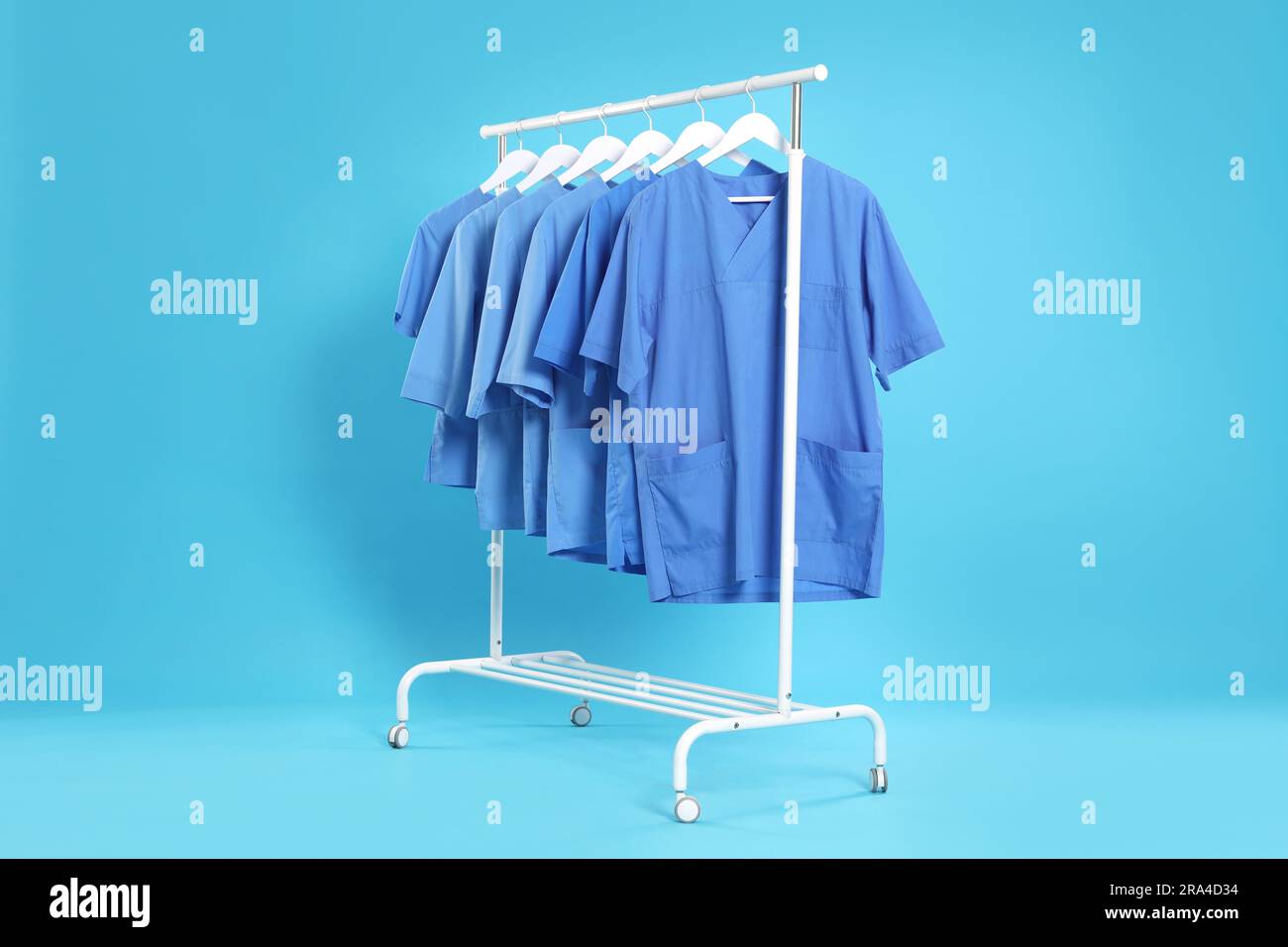 Medical uniforms on rack against light blue background Stock Photo - Alamy