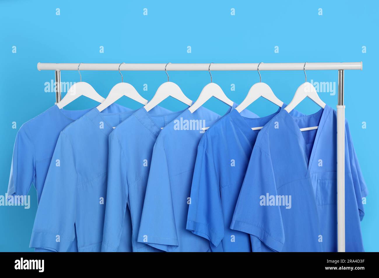 Medical uniforms on rack against light blue background Stock Photo - Alamy