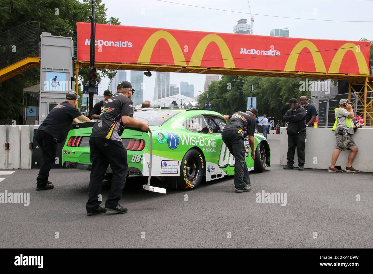 Pit crew workers walk the race cars to their designated spots and ...