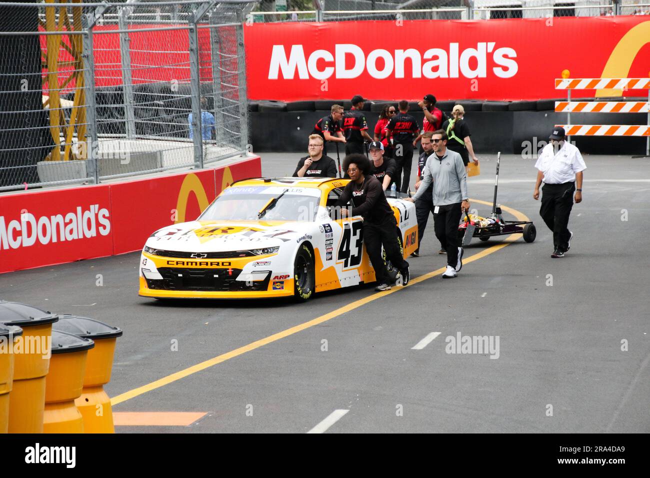 Pit crew workers walk the race cars to their designated spots and ...