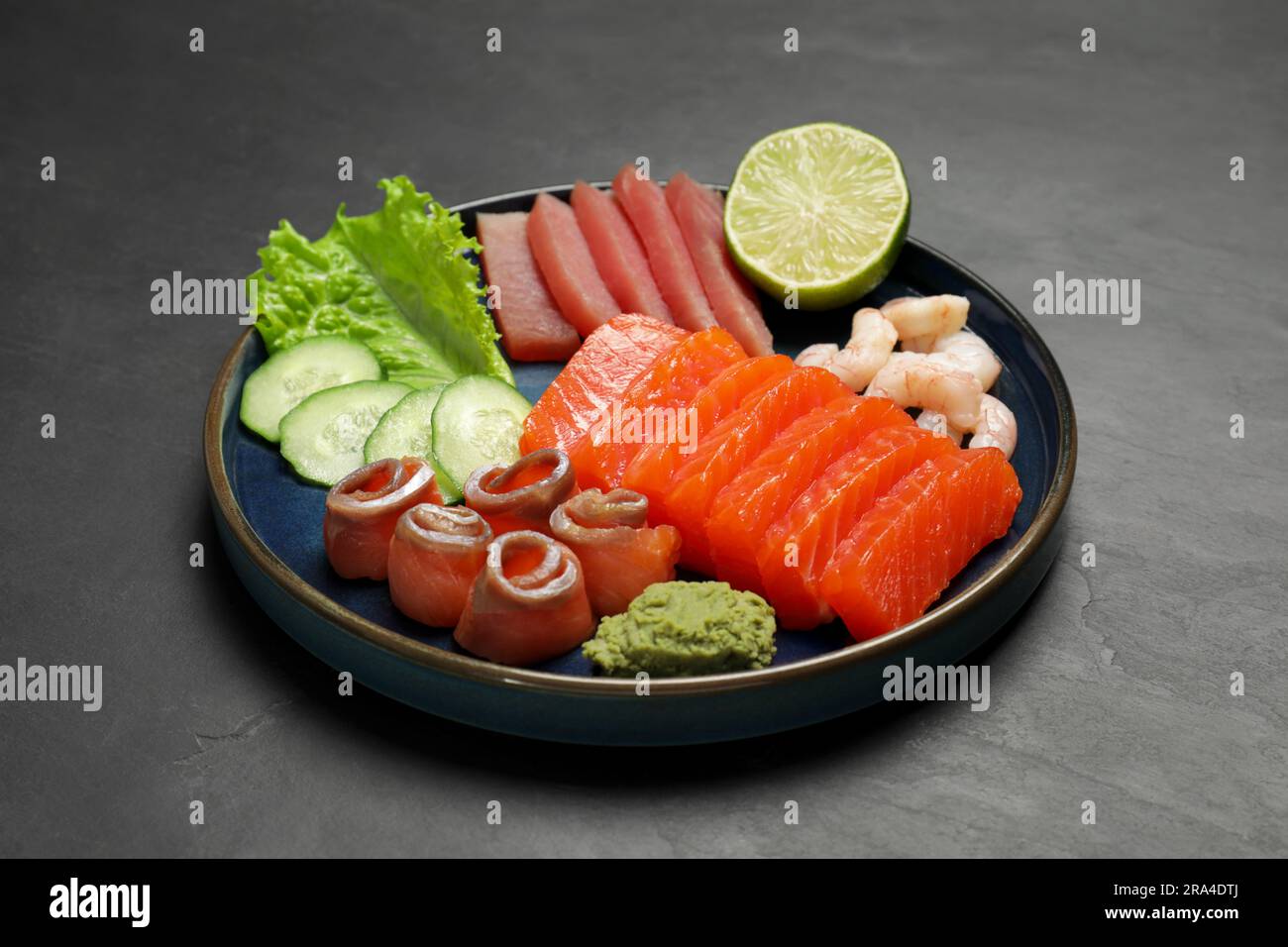 Tasty salmon slices, shrimp, cucumber and tuna on black table. Delicious sashimi dish Stock ...