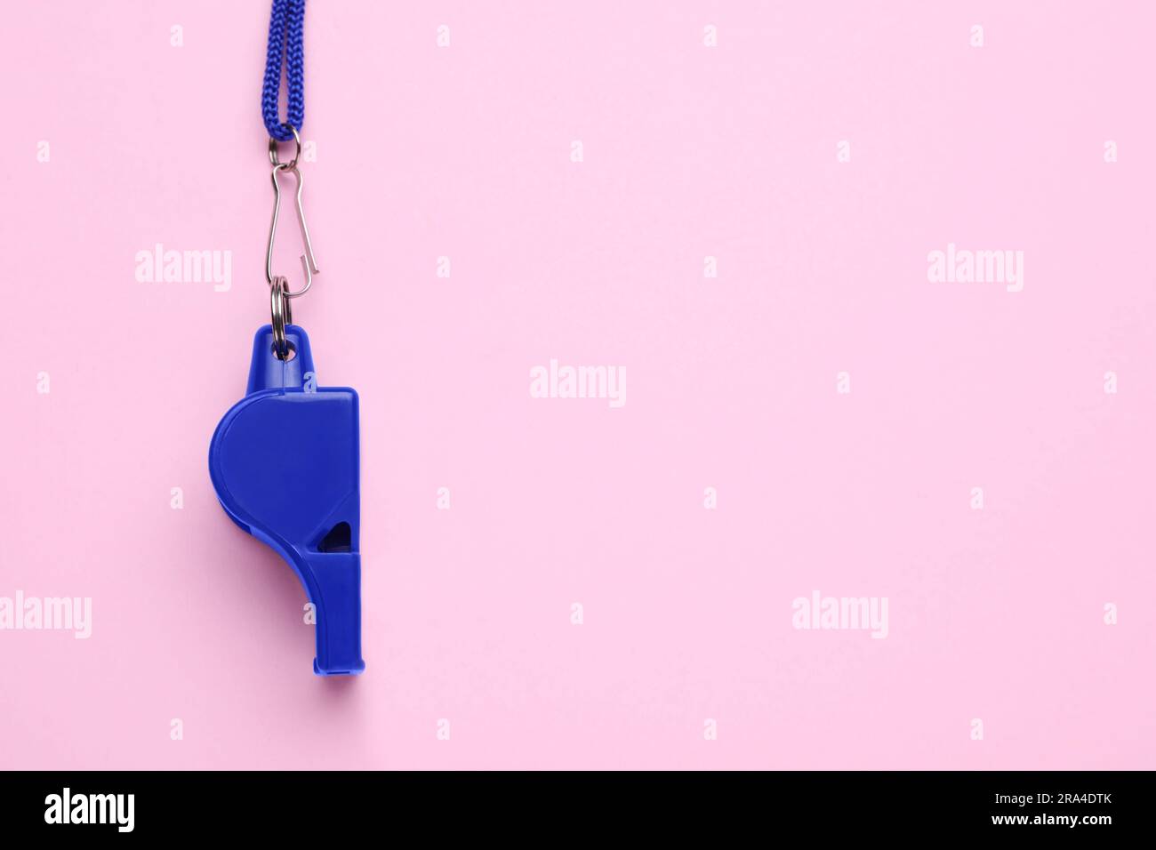 One blue whistle with cord on pink background, top view. Space for text ...