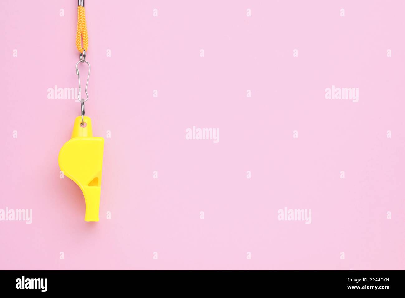 One yellow whistle with orange cord on pink background, top view. Space ...