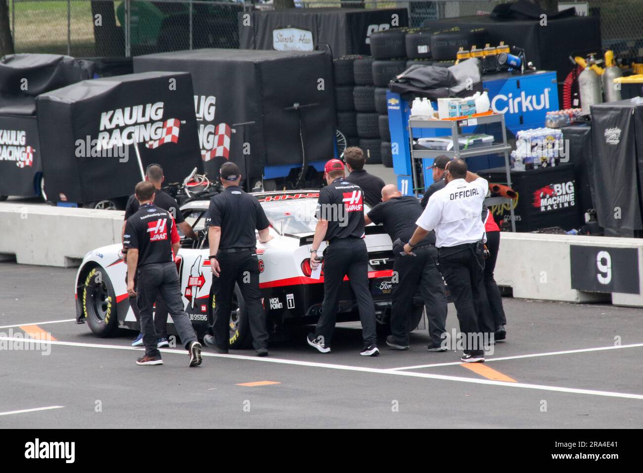 Pit crew workers walk the race cars to their designated spots and ...