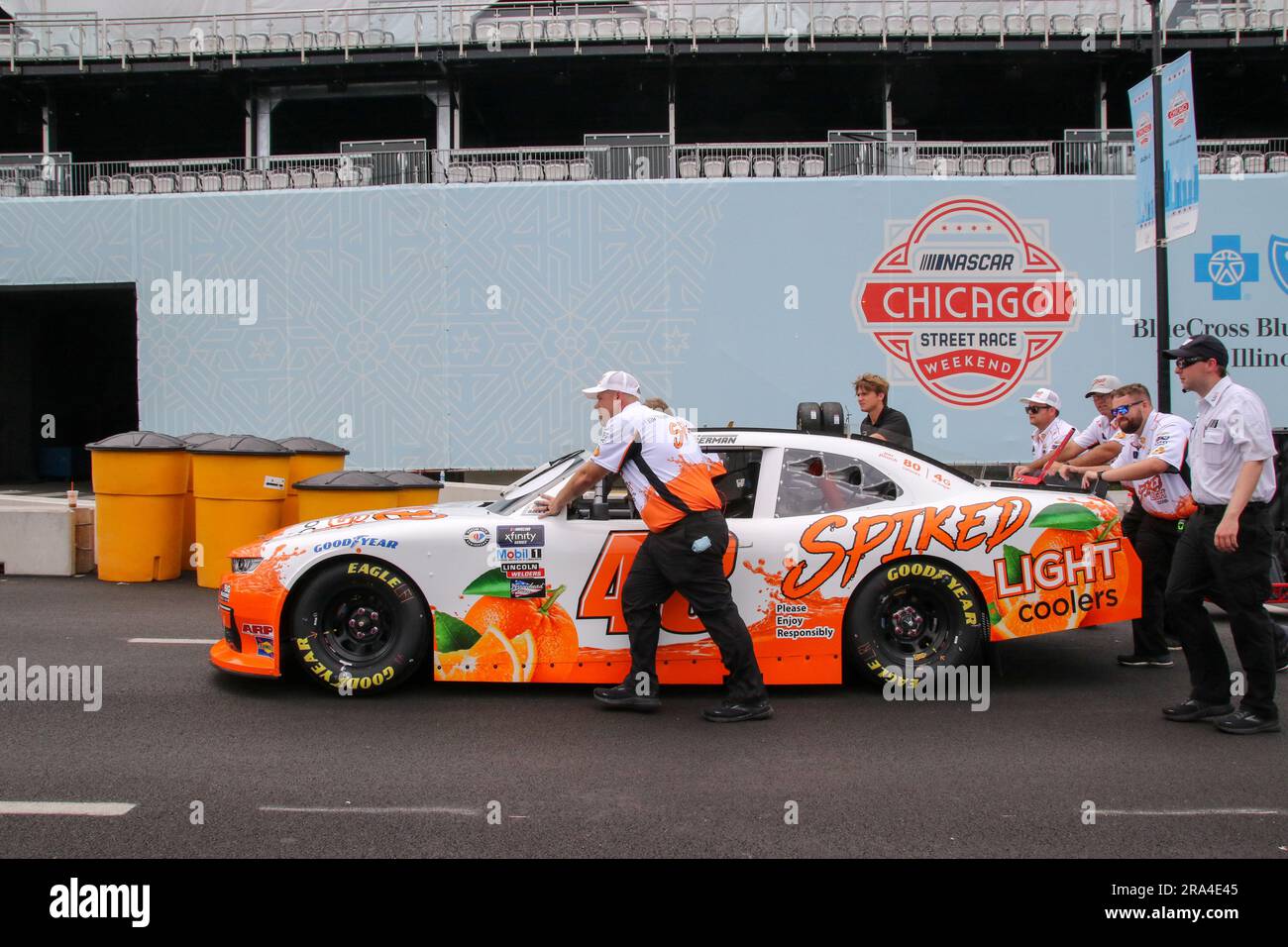 Pit crew workers walk the race cars to their designated spots and ...