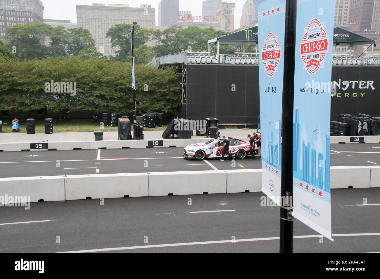 Pit crew workers walk the race cars to their designated spots and ...
