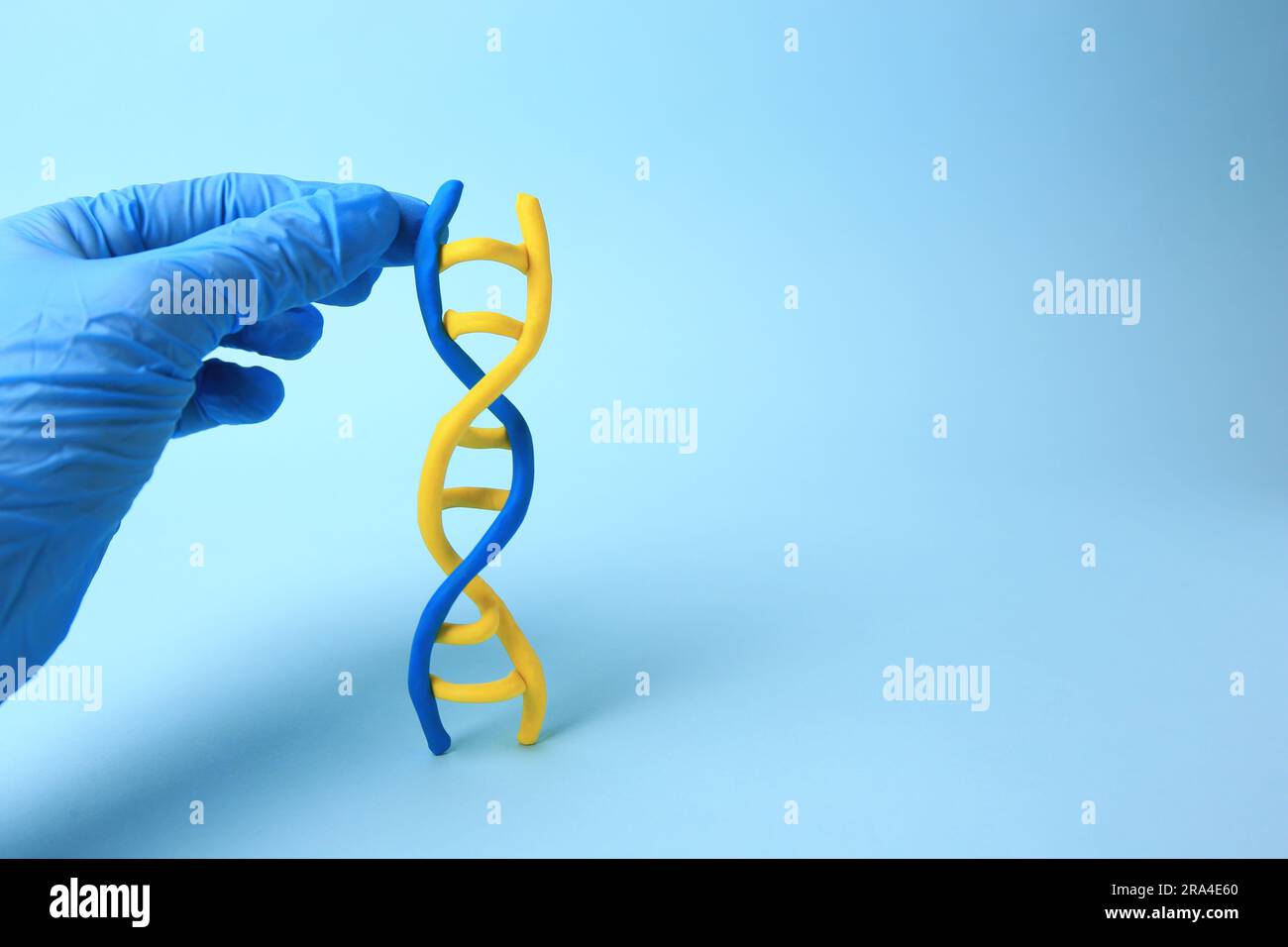Scientist with DNA molecule model made of plasticine on light blue ...