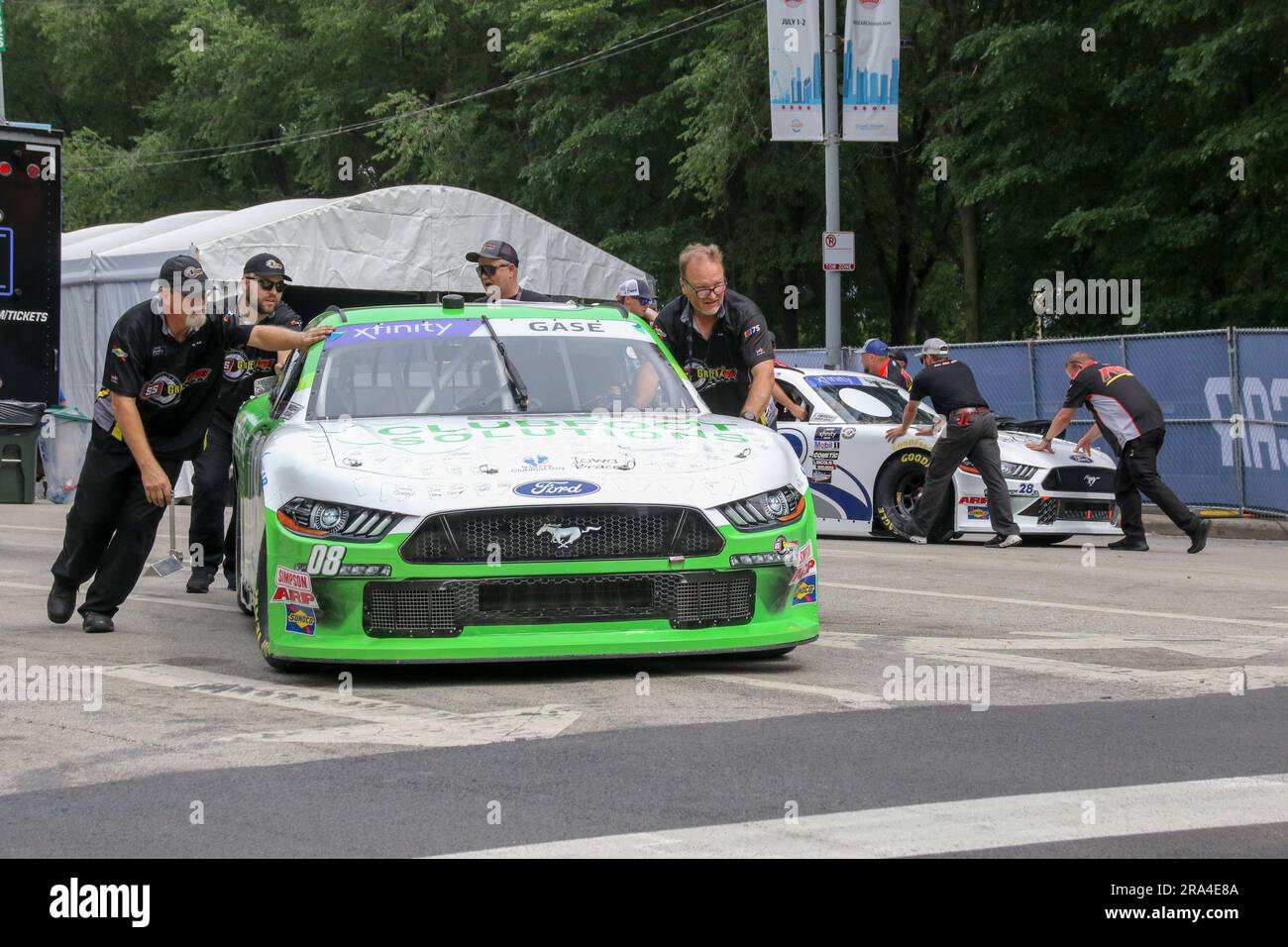 Pit crew workers walk the race cars to their designated spots and ...