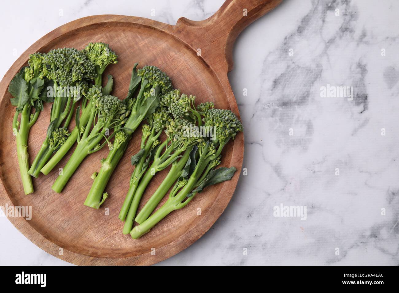 Fresh raw broccolini on white marble table, top view and space for text ...