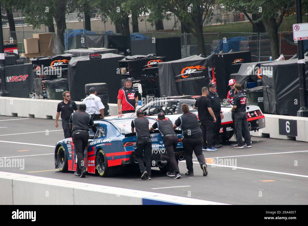 Pit crew workers walk the race cars to their designated spots and ...