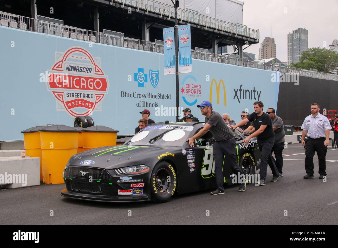 Pit crew workers walk the race cars to their designated spots and ...