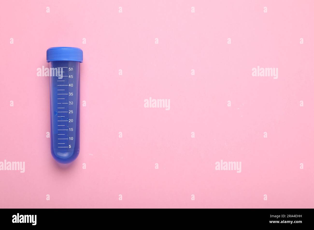 Test tube with liquid on pink background, top view and space for text ...