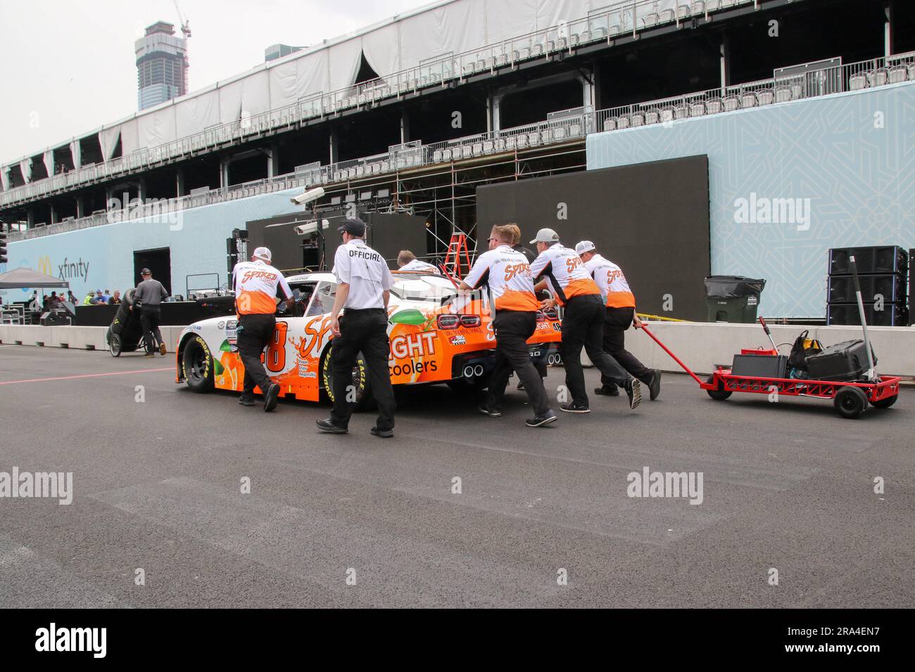 Pit crew workers walk the race cars to their designated spots and ...