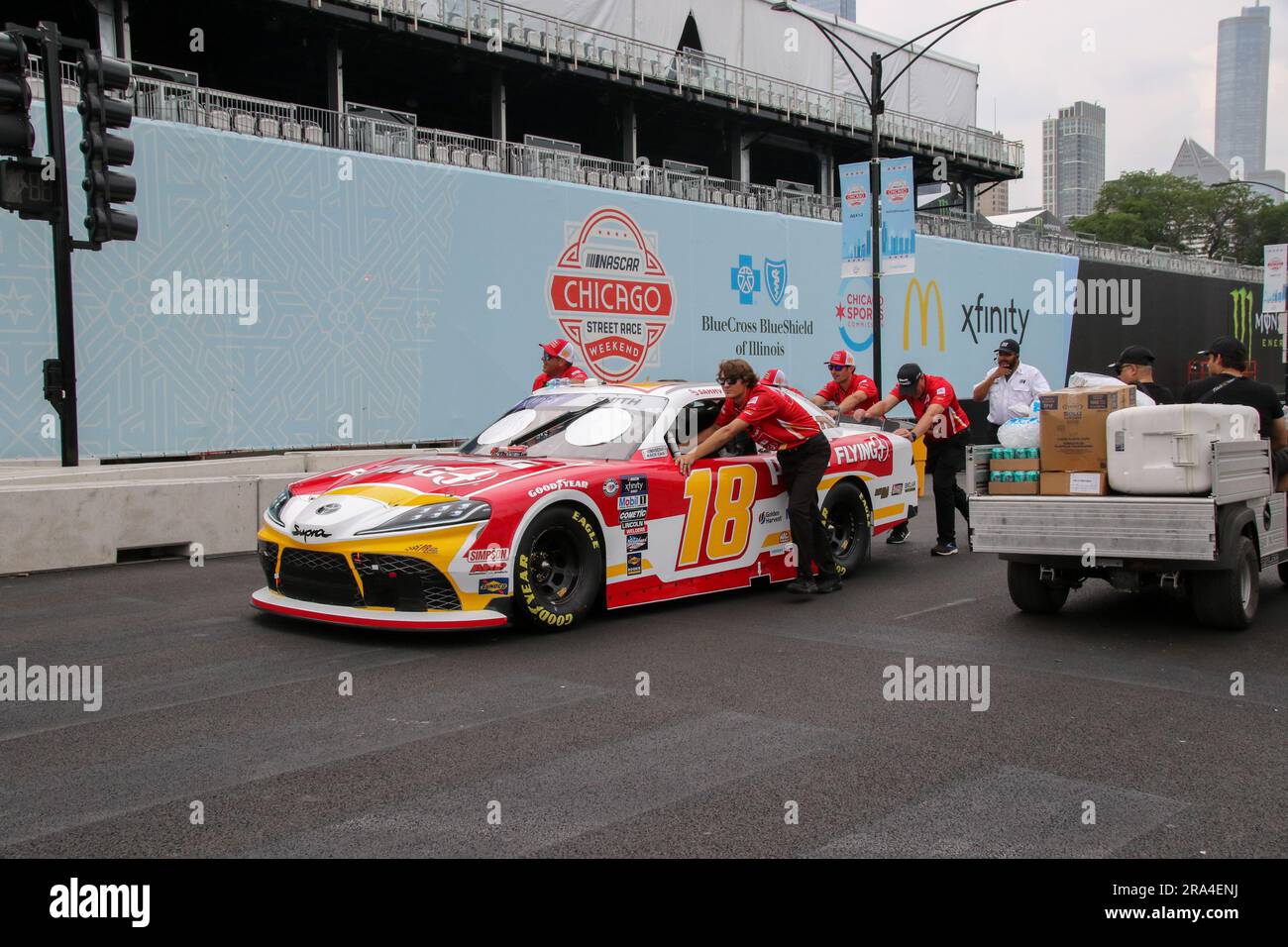 Pit crew workers walk the race cars to their designated spots and ...