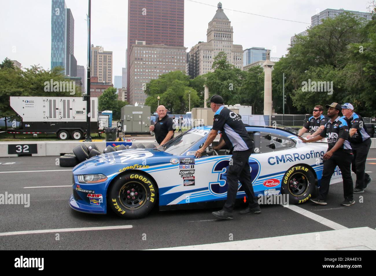 Pit crew workers walk the race cars to their designated spots and ...
