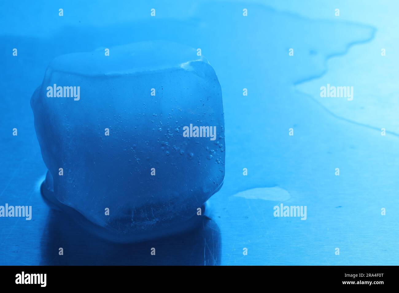 Crystal clear ice cube on light blue background, closeup with space for text. Color tone effect ...