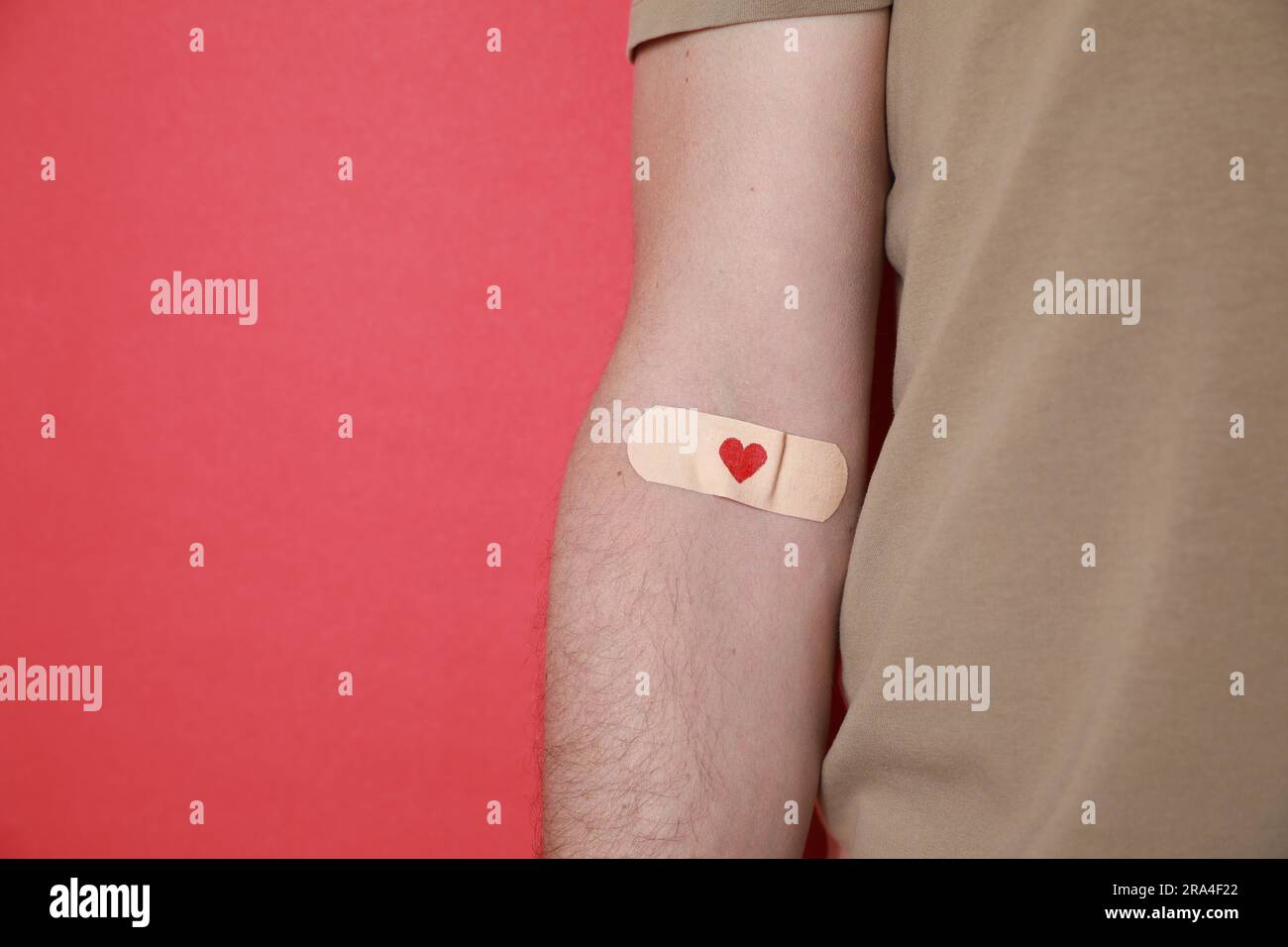 Blood donation concept. Man with adhesive plaster on arm against red ...