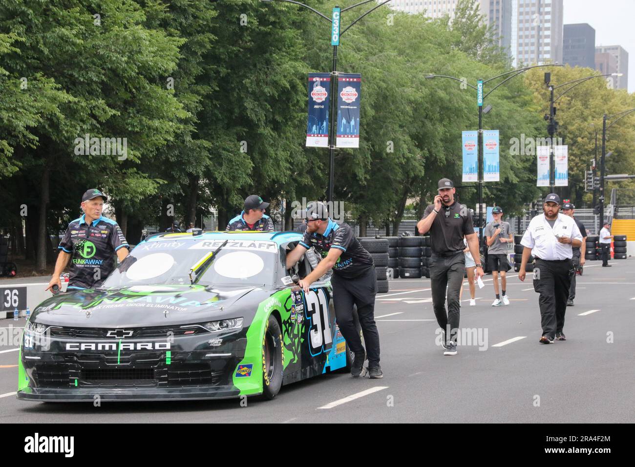 Pit crew workers walk the race cars to their designated spots and ...