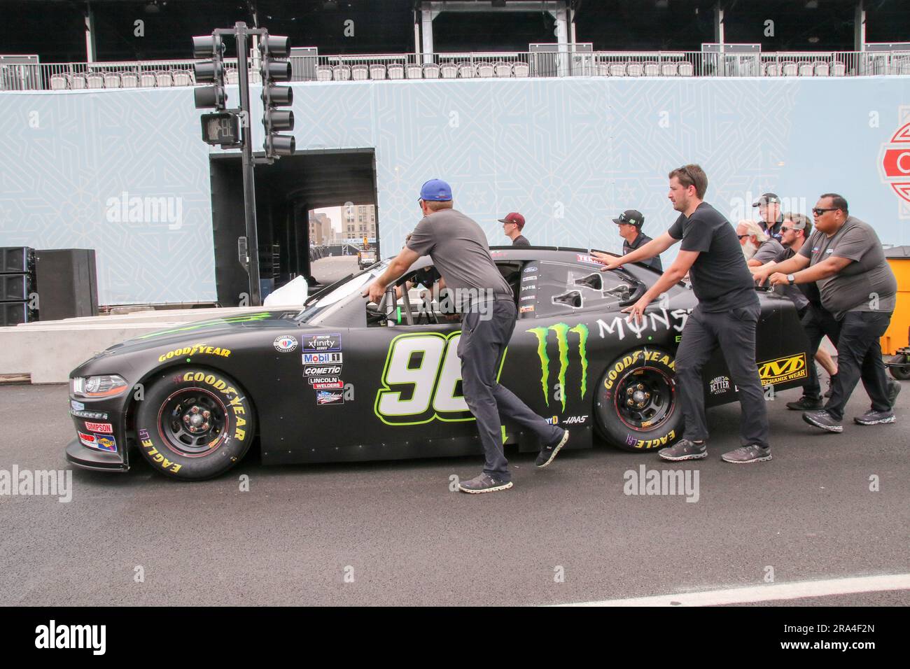 Pit crew workers walk the race cars to their designated spots and ...
