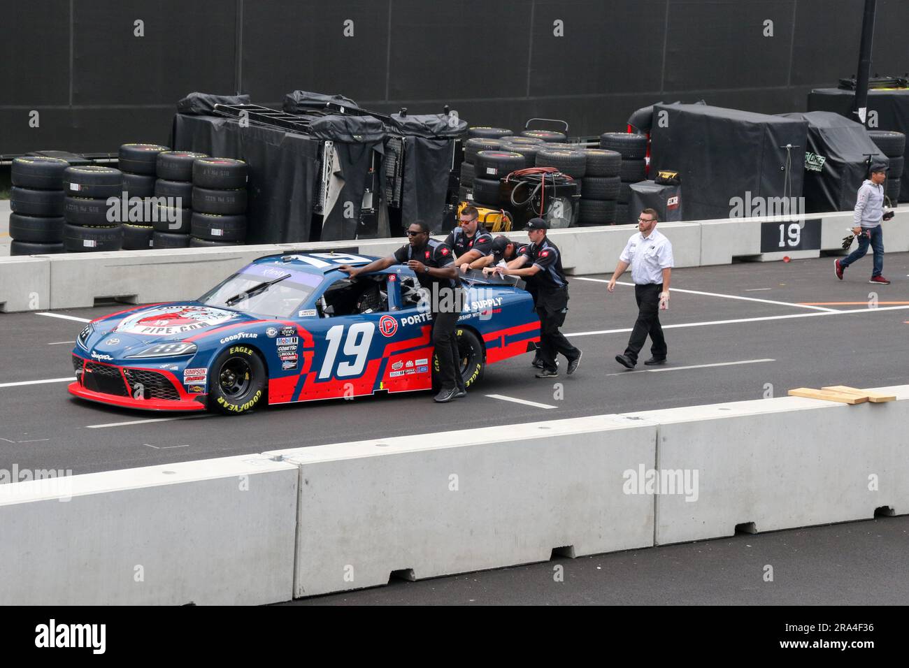 Pit crew workers walk the race cars to their designated spots and ...