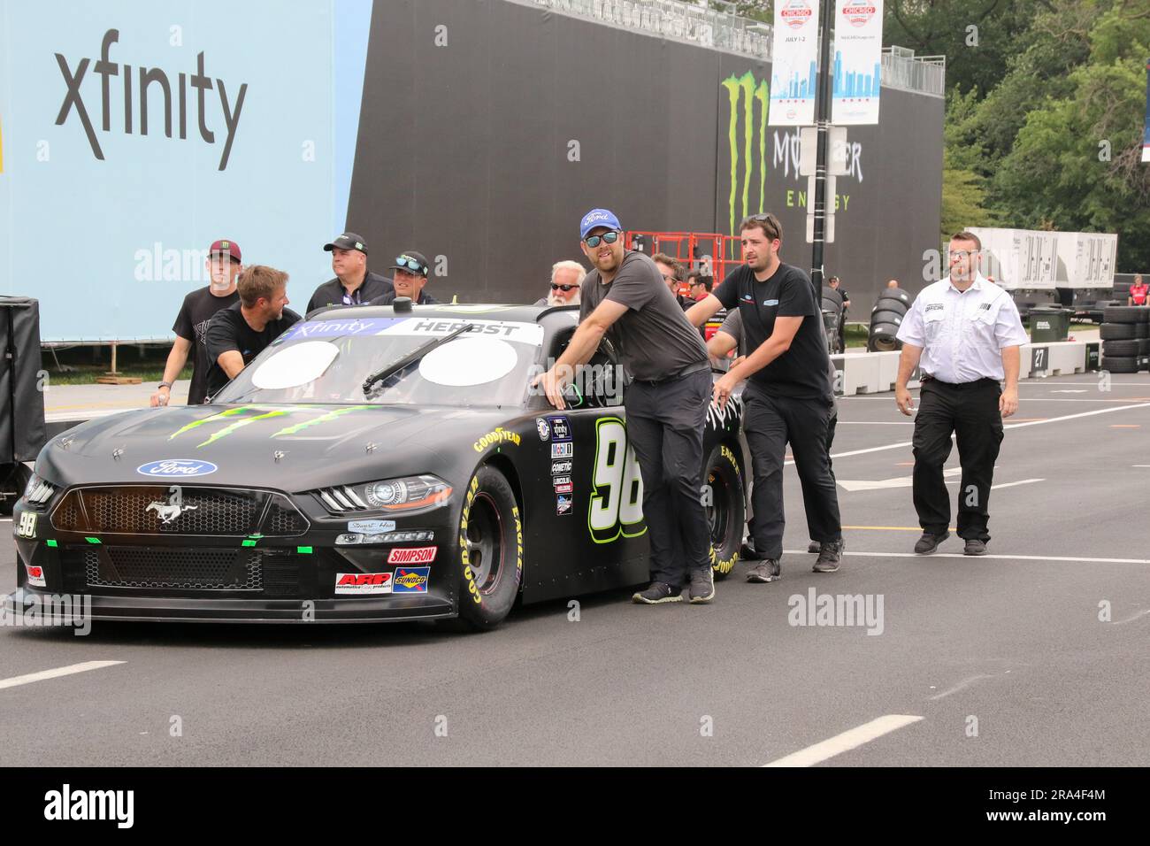 Pit crew workers walk the race cars to their designated spots and ...