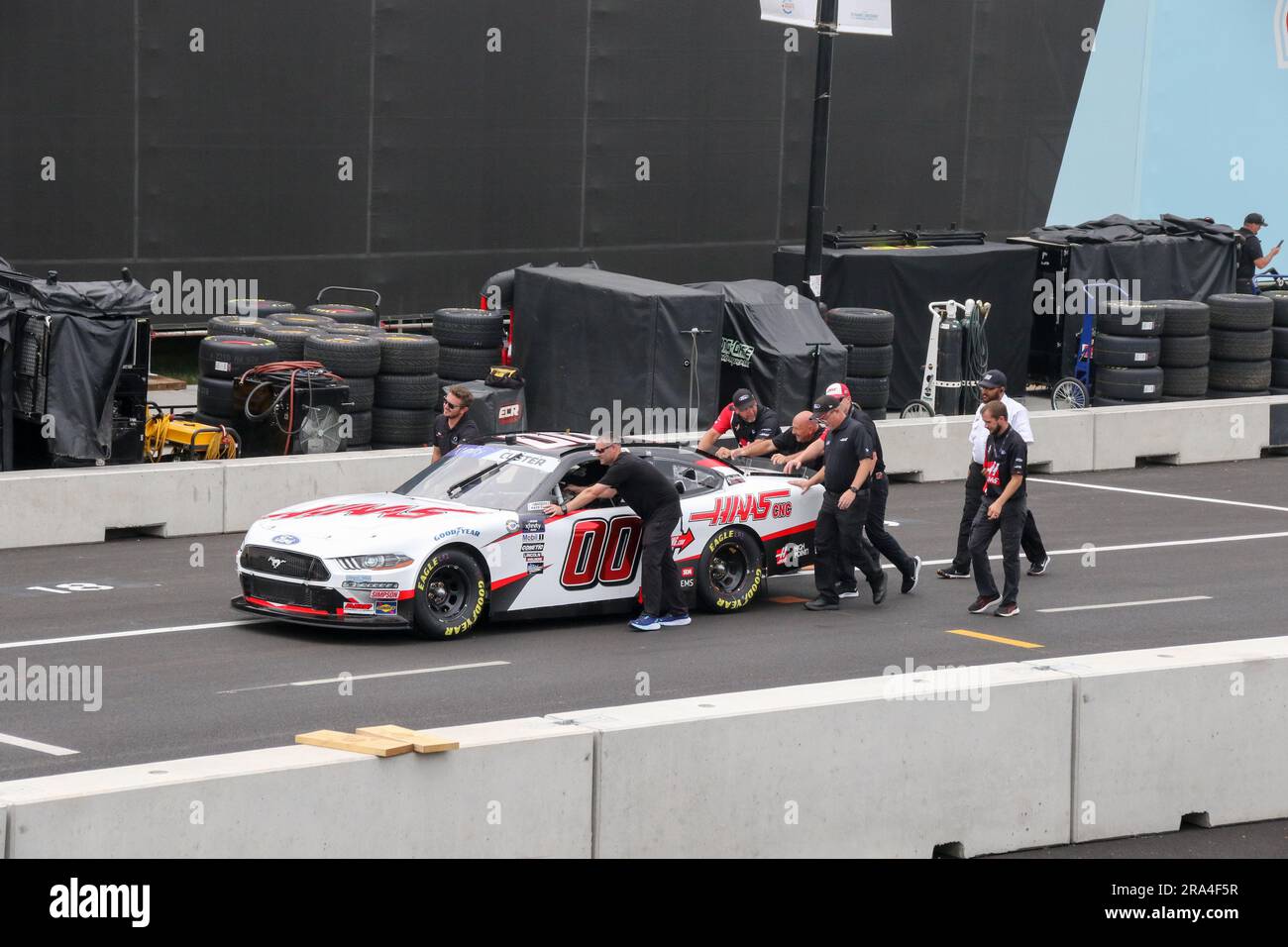 Pit crew workers walk the race cars to their designated spots and ...