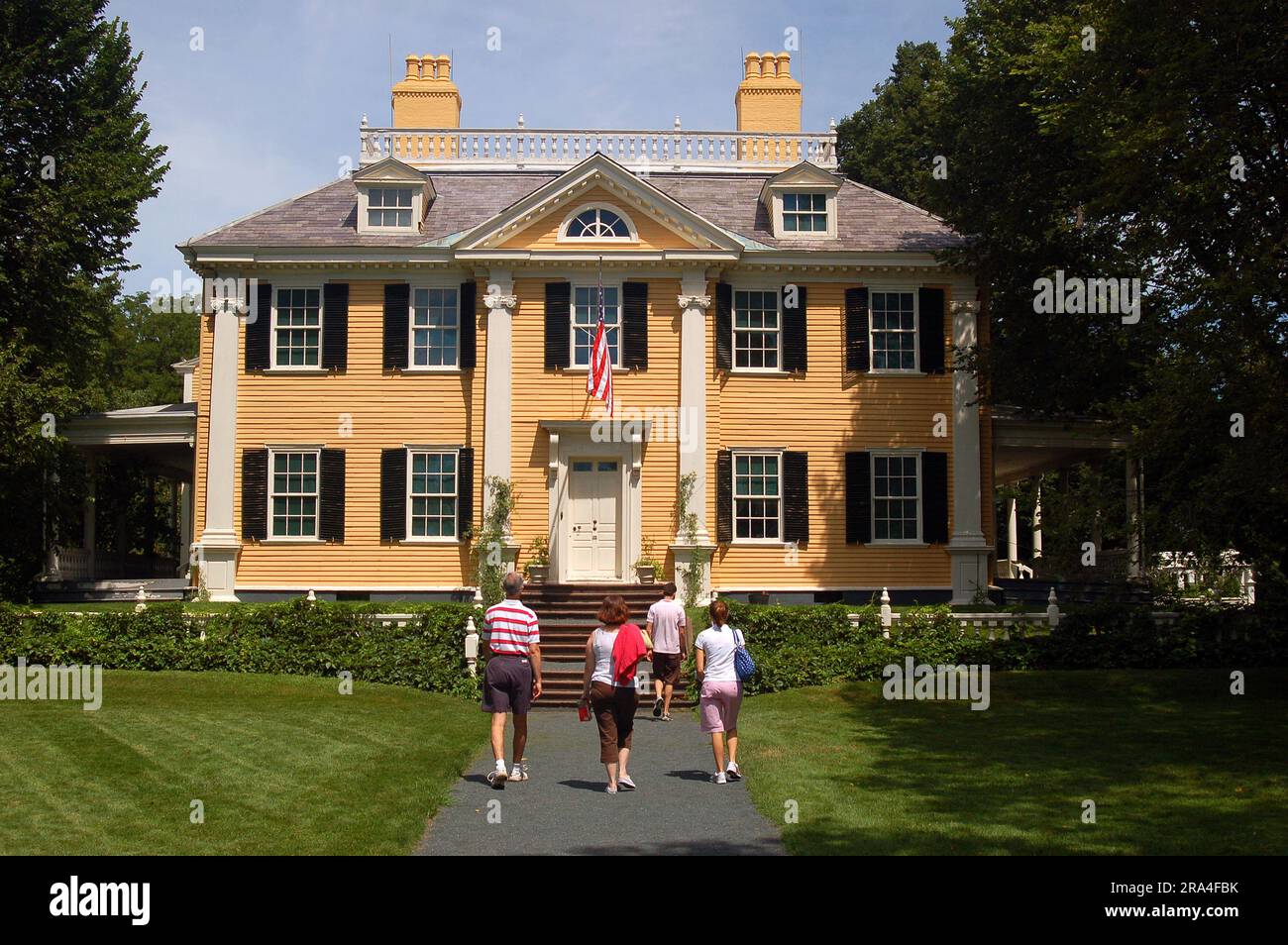 A family walks up to the front door of the yellow Longfellow House, a ...