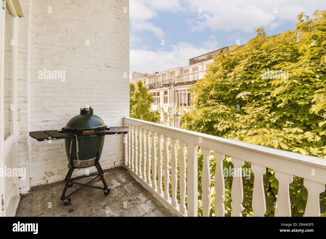 a grill sitting on the porch in front of a white brick building with ...