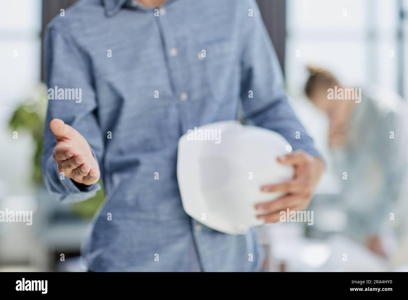 Architect and civil engineer shaking hands while holding hard hat in ...