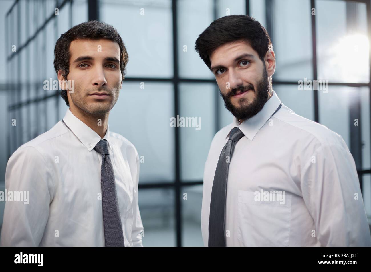 Two serious young businessmen standing with in office Stock Photo - Alamy