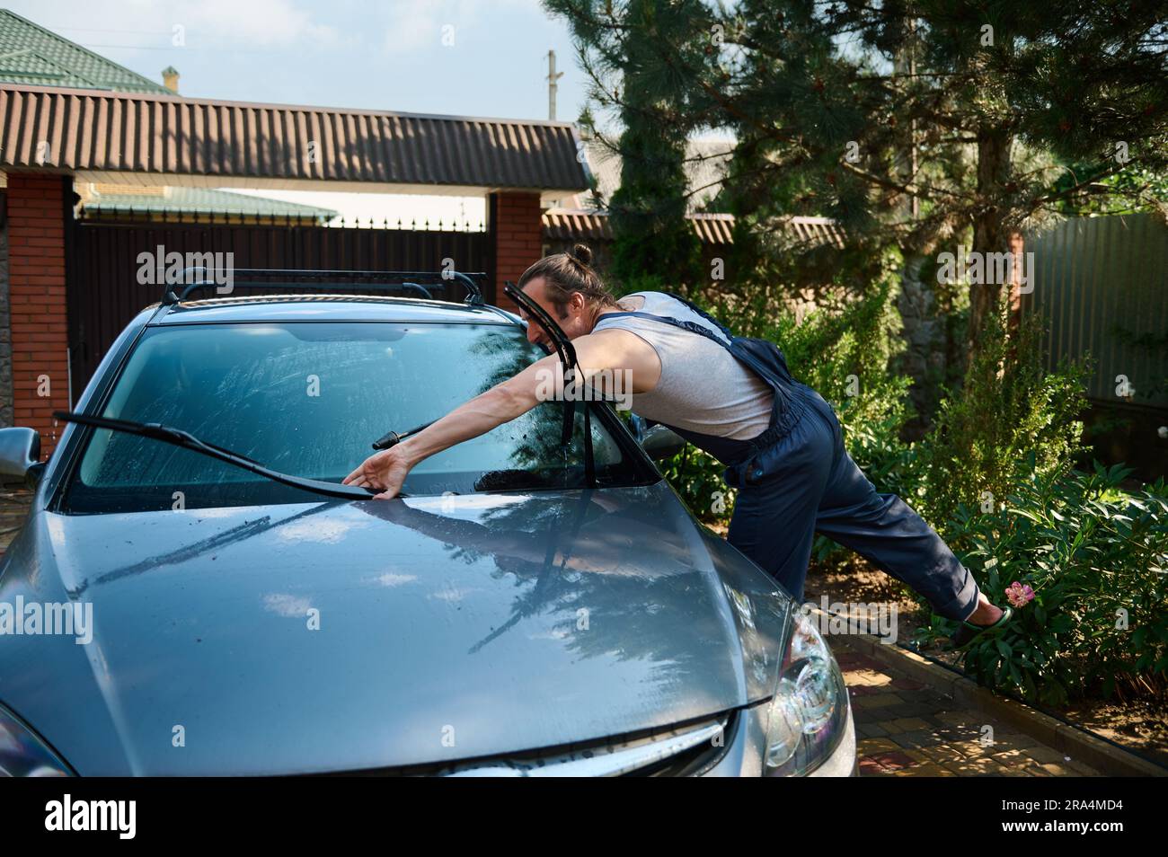 Handsome muscular man washing his car with a high pressure cleaning ...