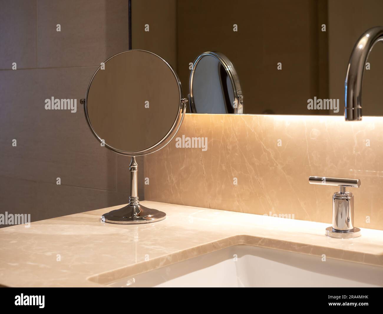 Small folding round makeup mirror standing near sink basin with marble ...